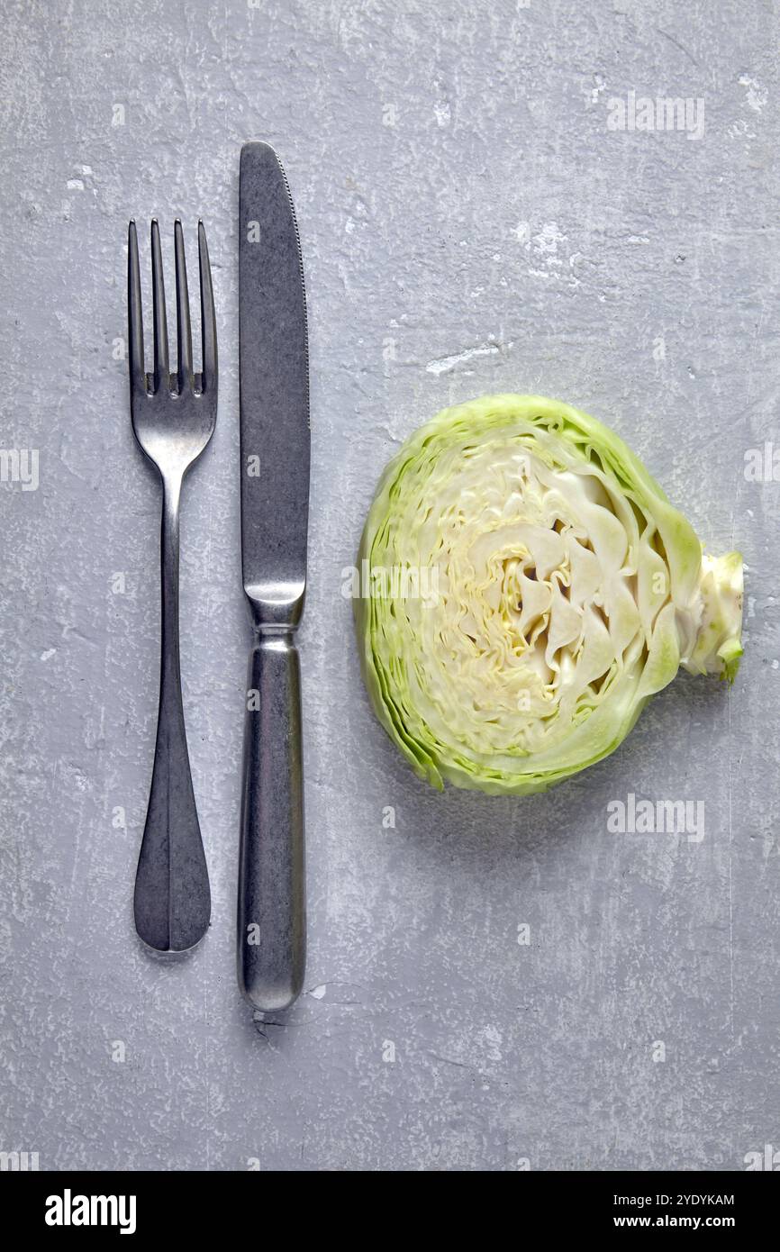 cabbage cut across and cutlery fork and knife on grey concrete table ...
