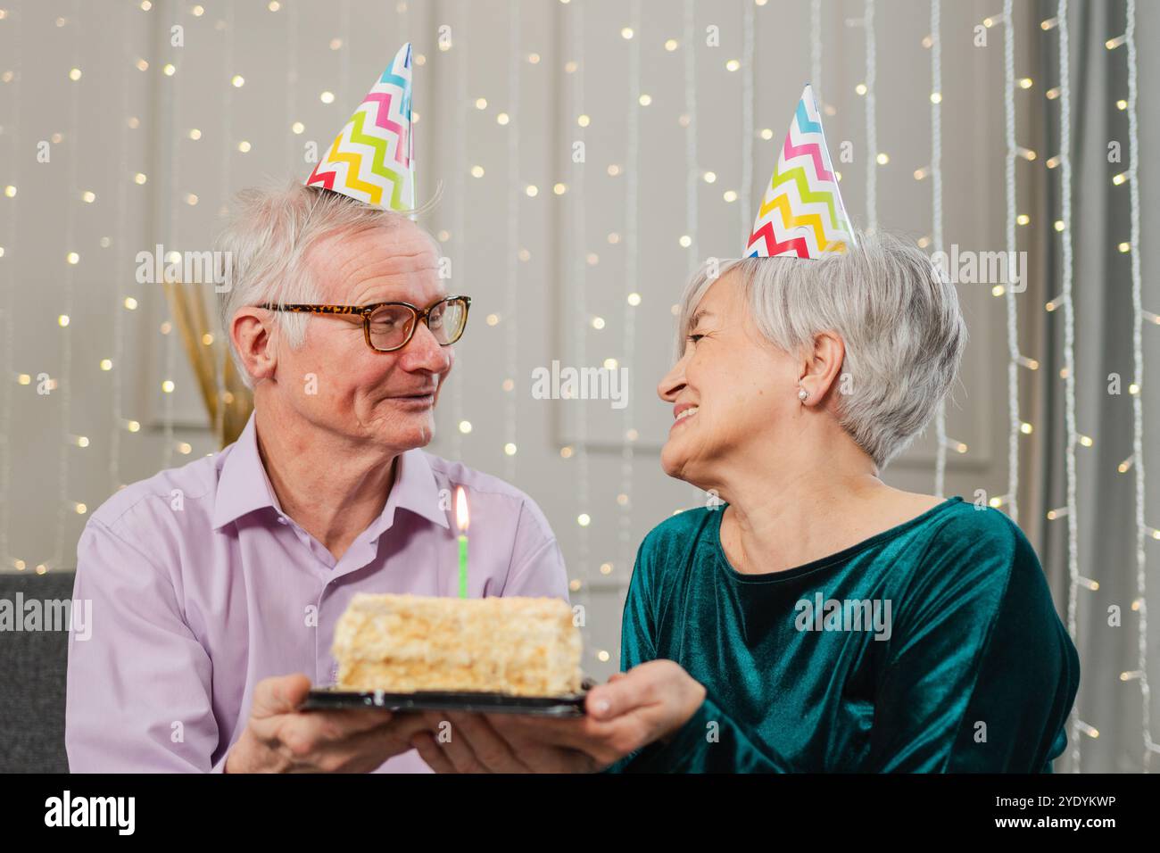 Make a wish. Family senior couple in party hat cap celebrating birthday ...