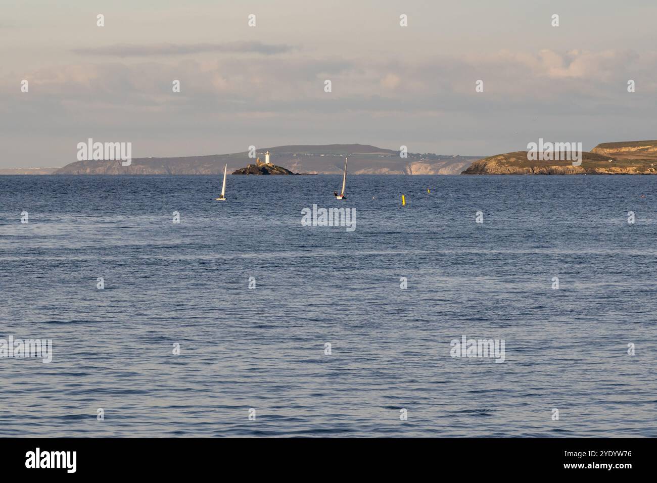 People sail dinghies in St Ives Bay, with Godrevy Lighthouse and St ...