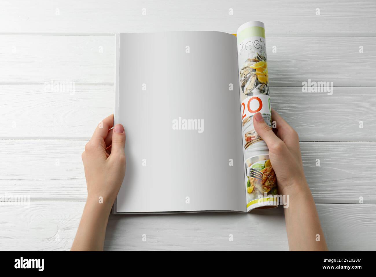 Woman reading magazine at white wooden table, top view. Mockup for ...
