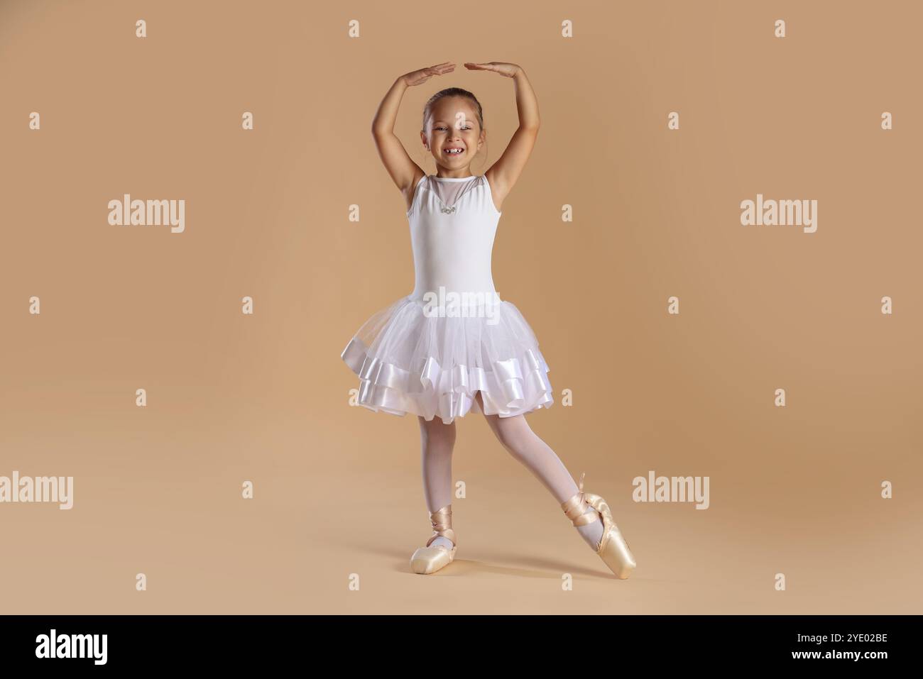 Little ballerina practicing dance moves on beige background Stock Photo ...