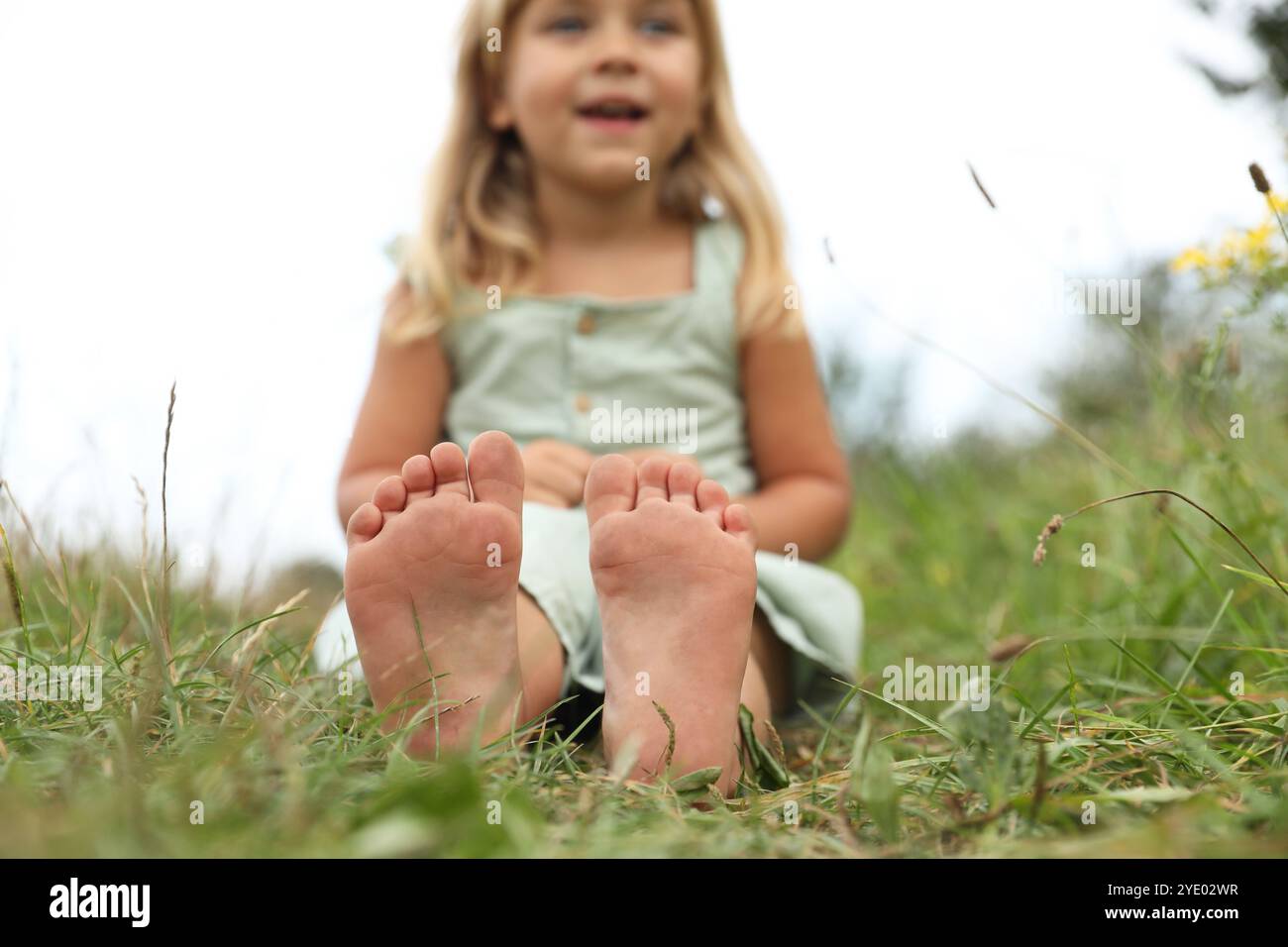 Barefoot little girl on green grass at meadow, selective focus. Child ...