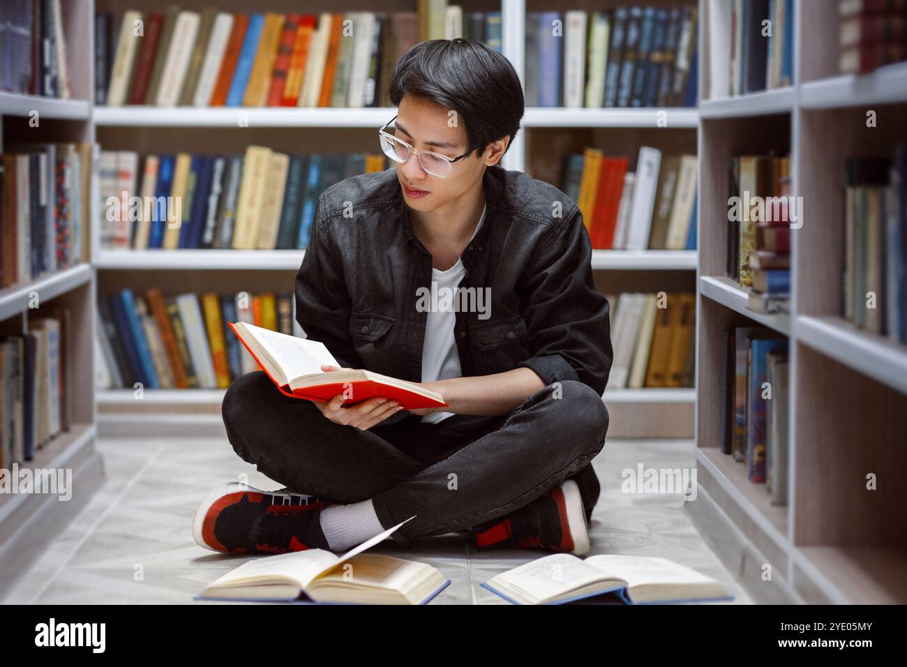 Focused chinese guy reading books at library Stock Photo - Alamy