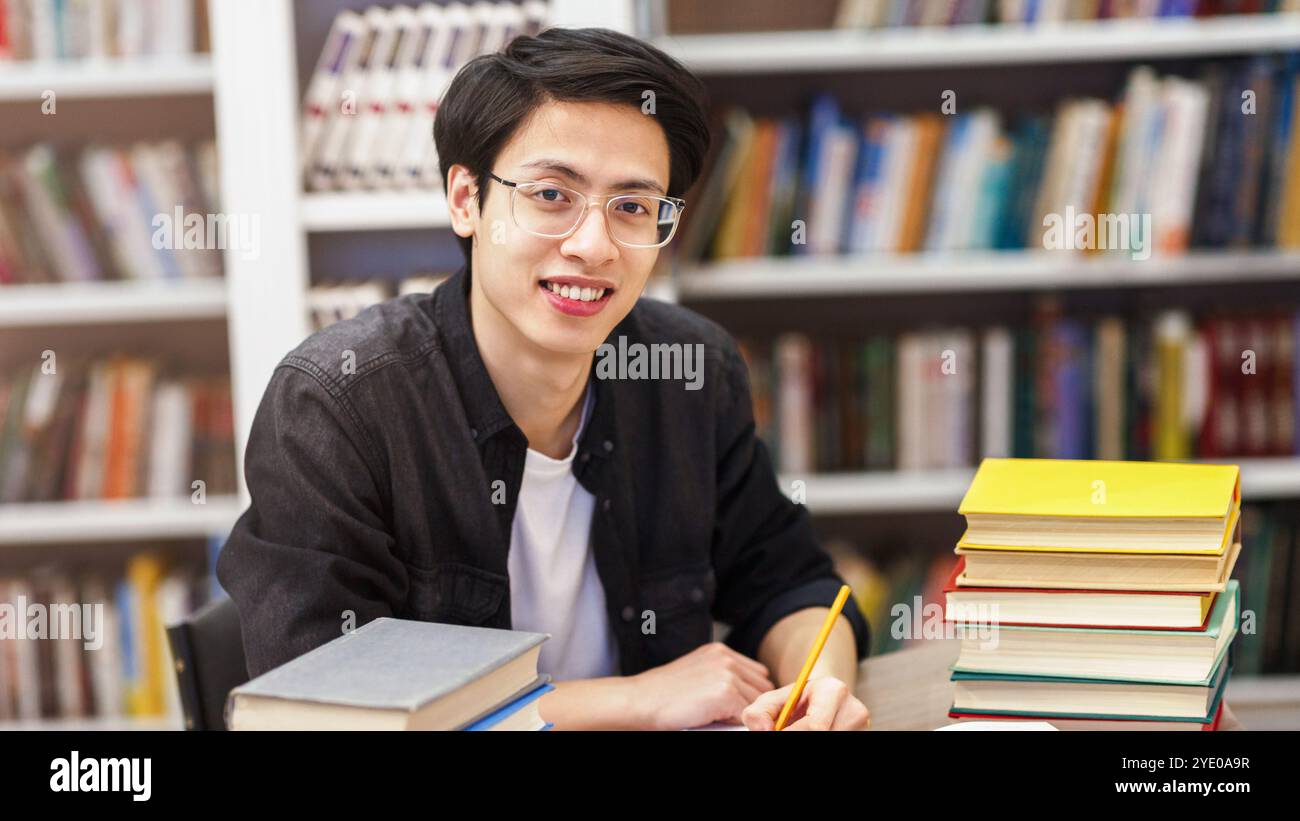 Smiling chinese man sitting at desk in library Stock Photo - Alamy