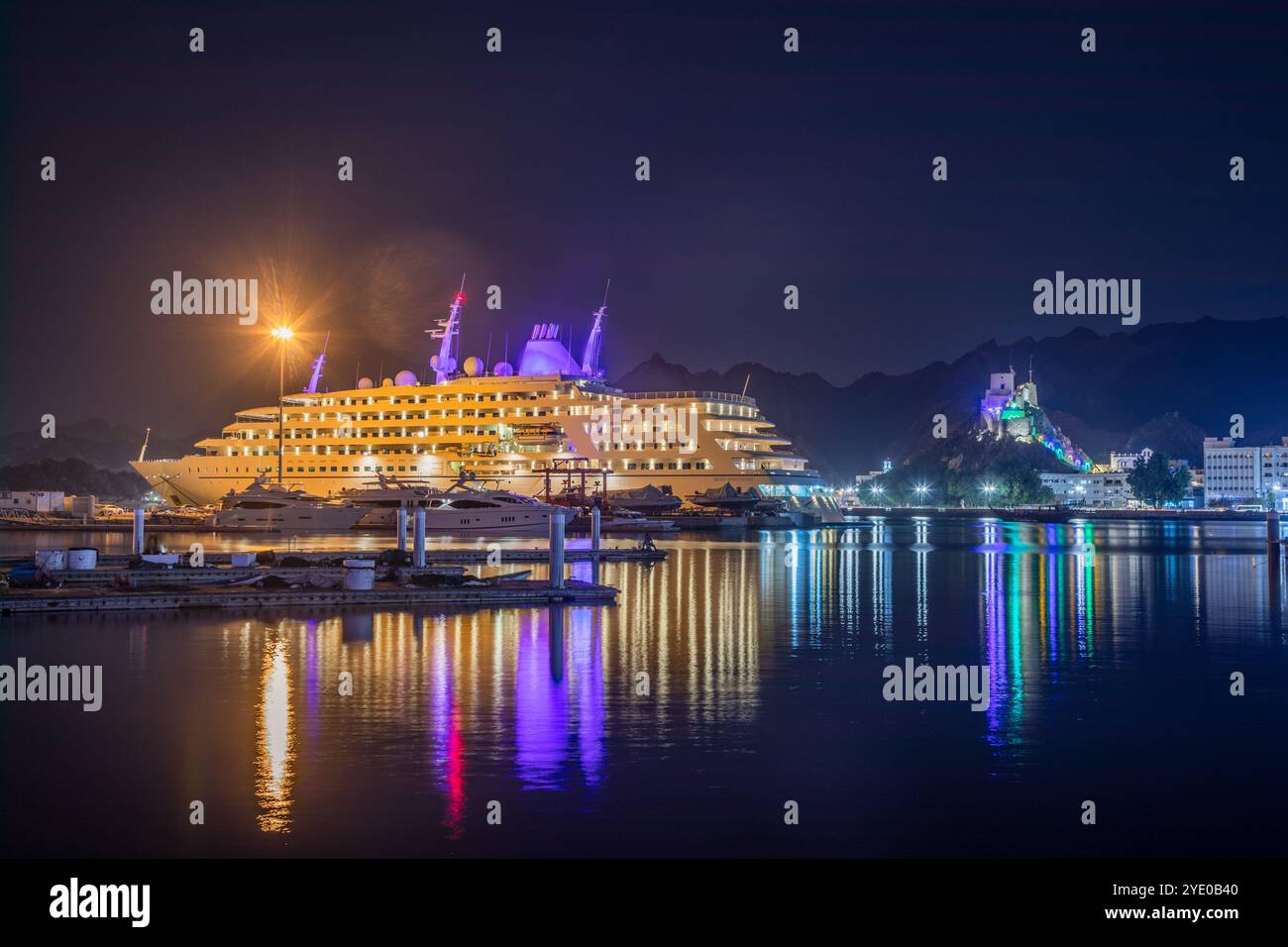 Night corniche promenade with illuminated Mutrah castle on the hill and ...