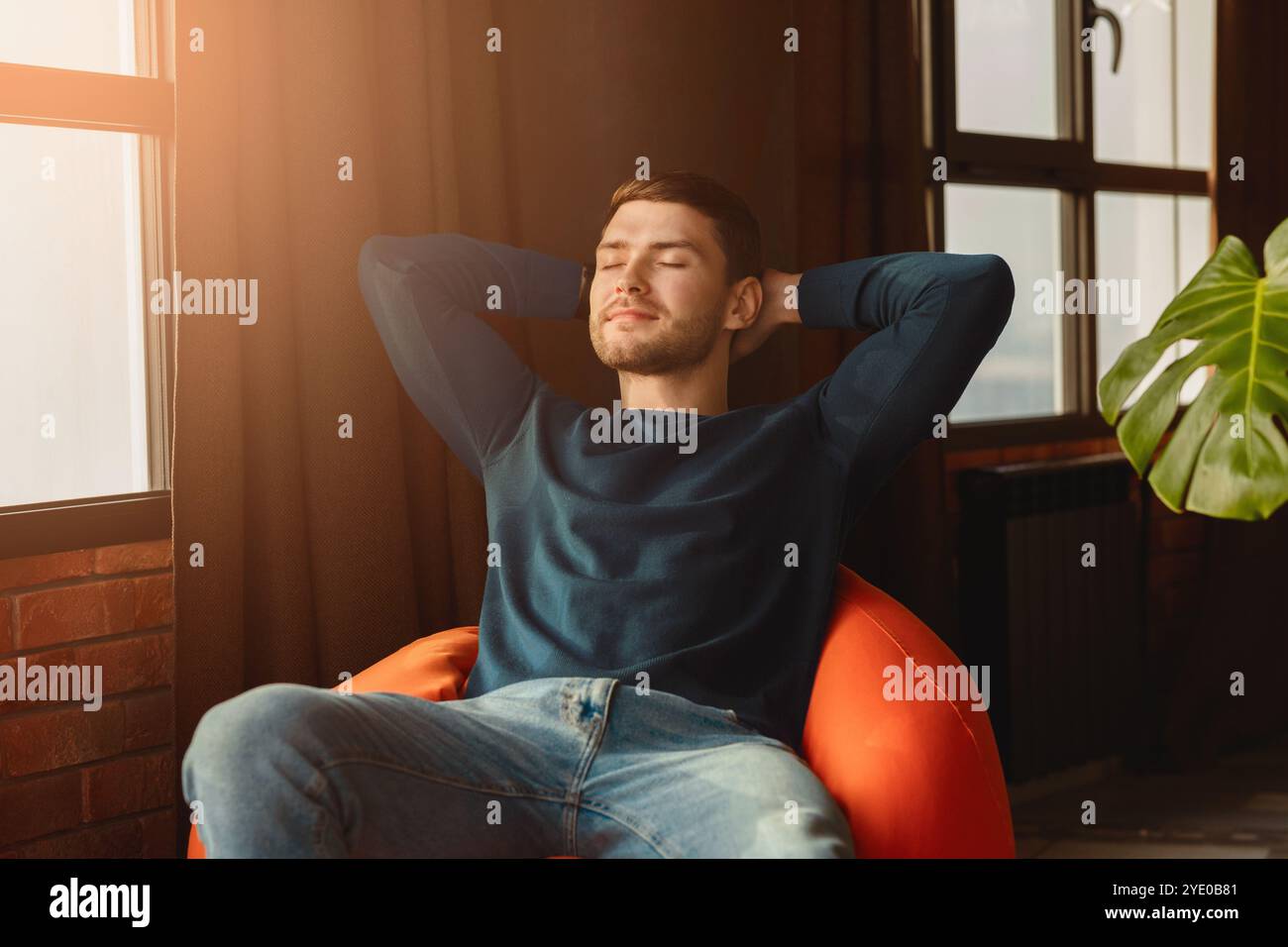 Relaxed Millennial Guy Sitting On Beanbag Chair In Modern Interior ...