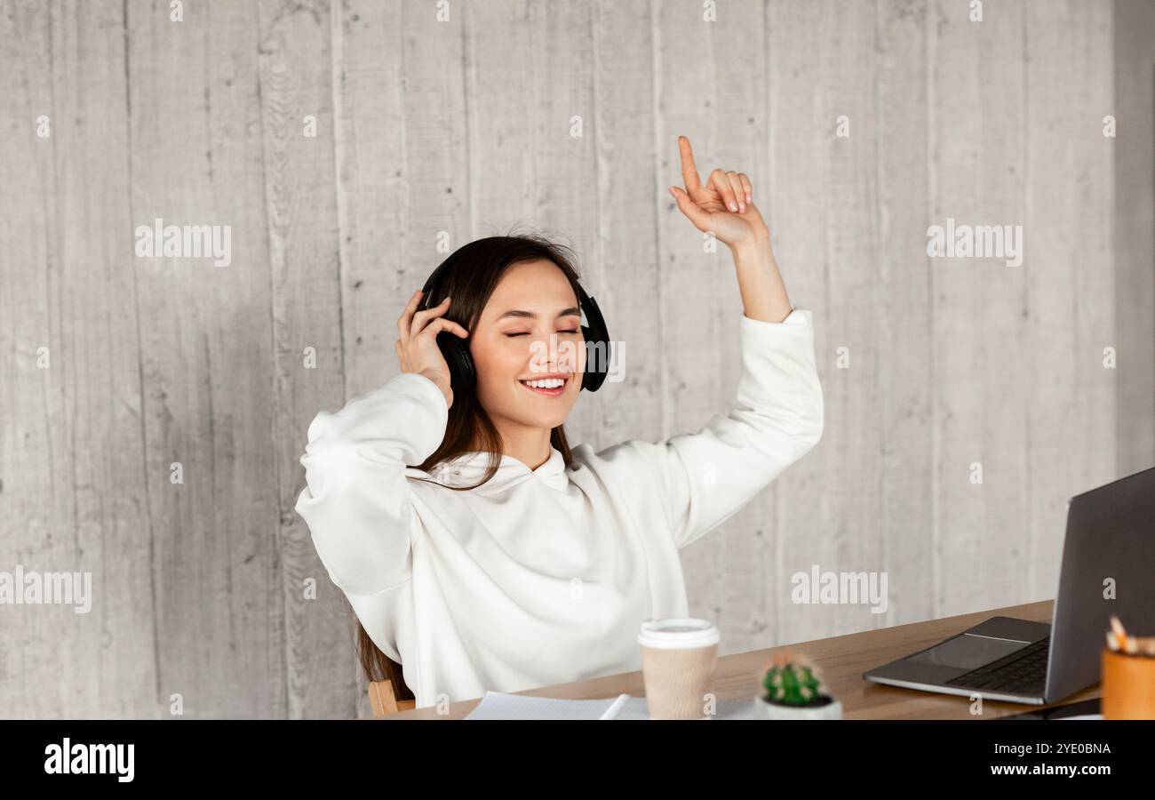Music break. Girl in workplace raises her hand up Stock Photo - Alamy