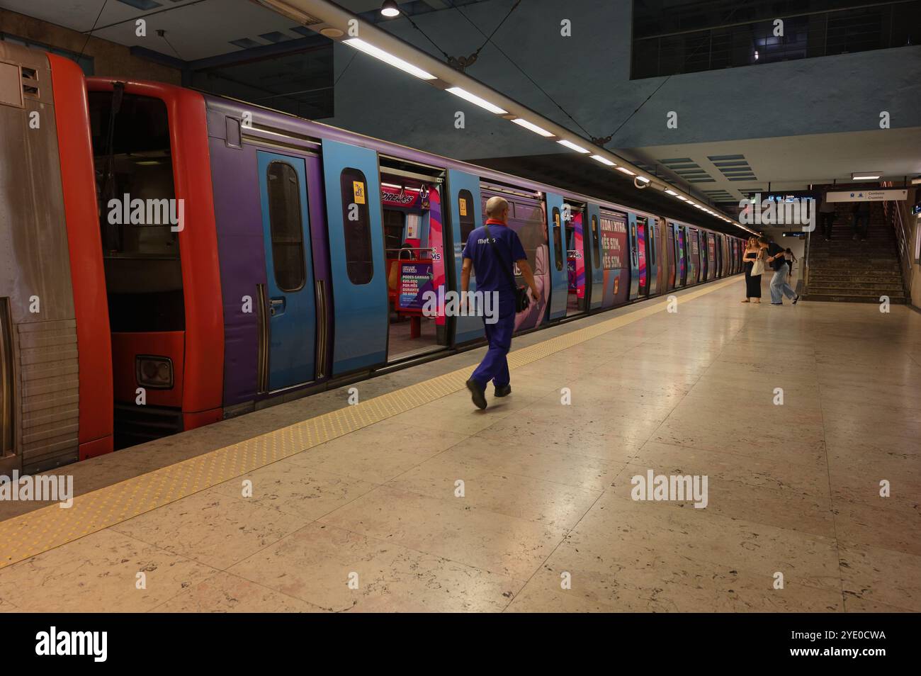 Metro employee walks along the colorful train at Santa Apolónia station ...