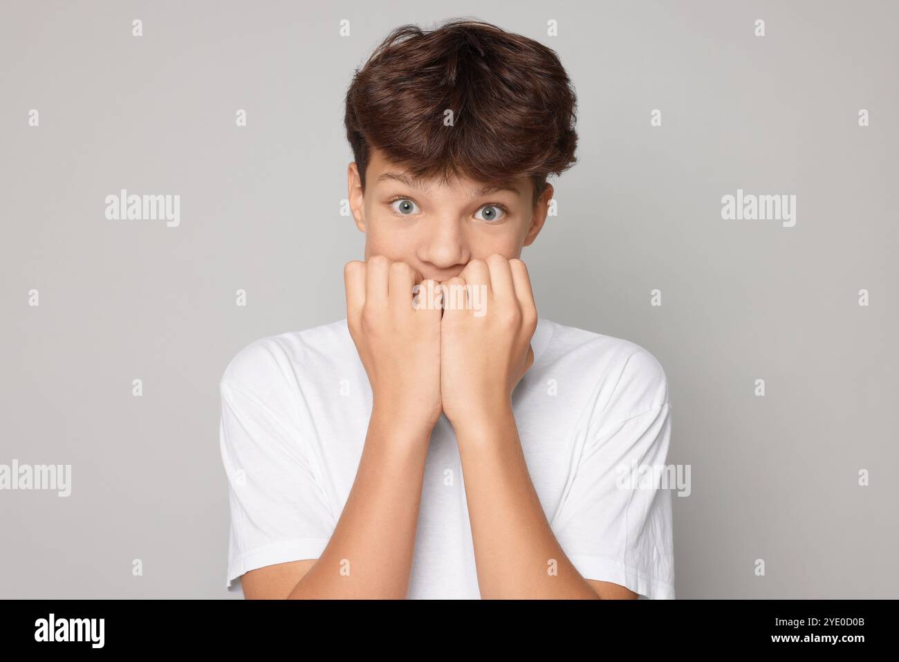 Portrait of scared teenage boy on grey background Stock Photo - Alamy