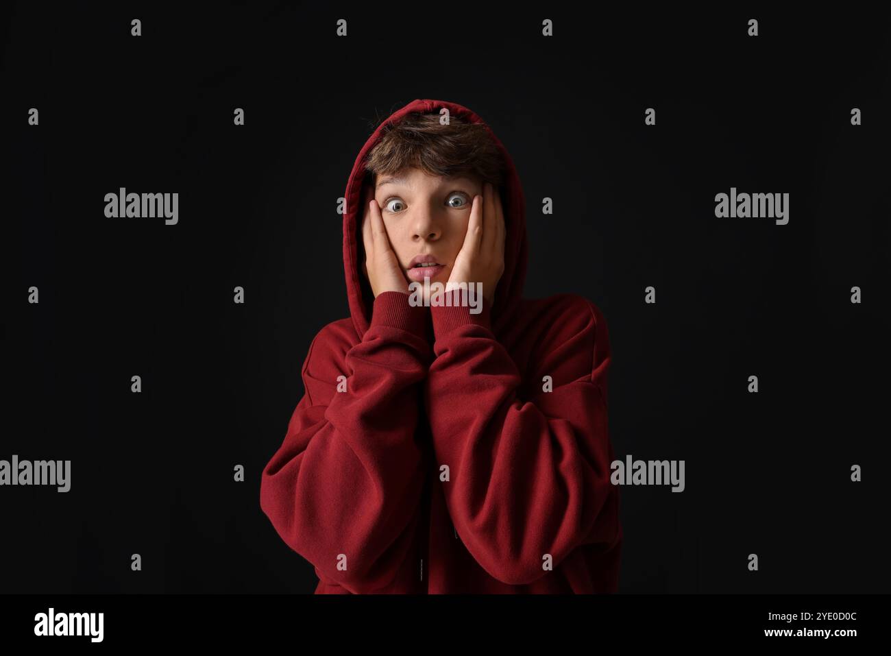 Portrait of scared teenage boy on black background Stock Photo - Alamy