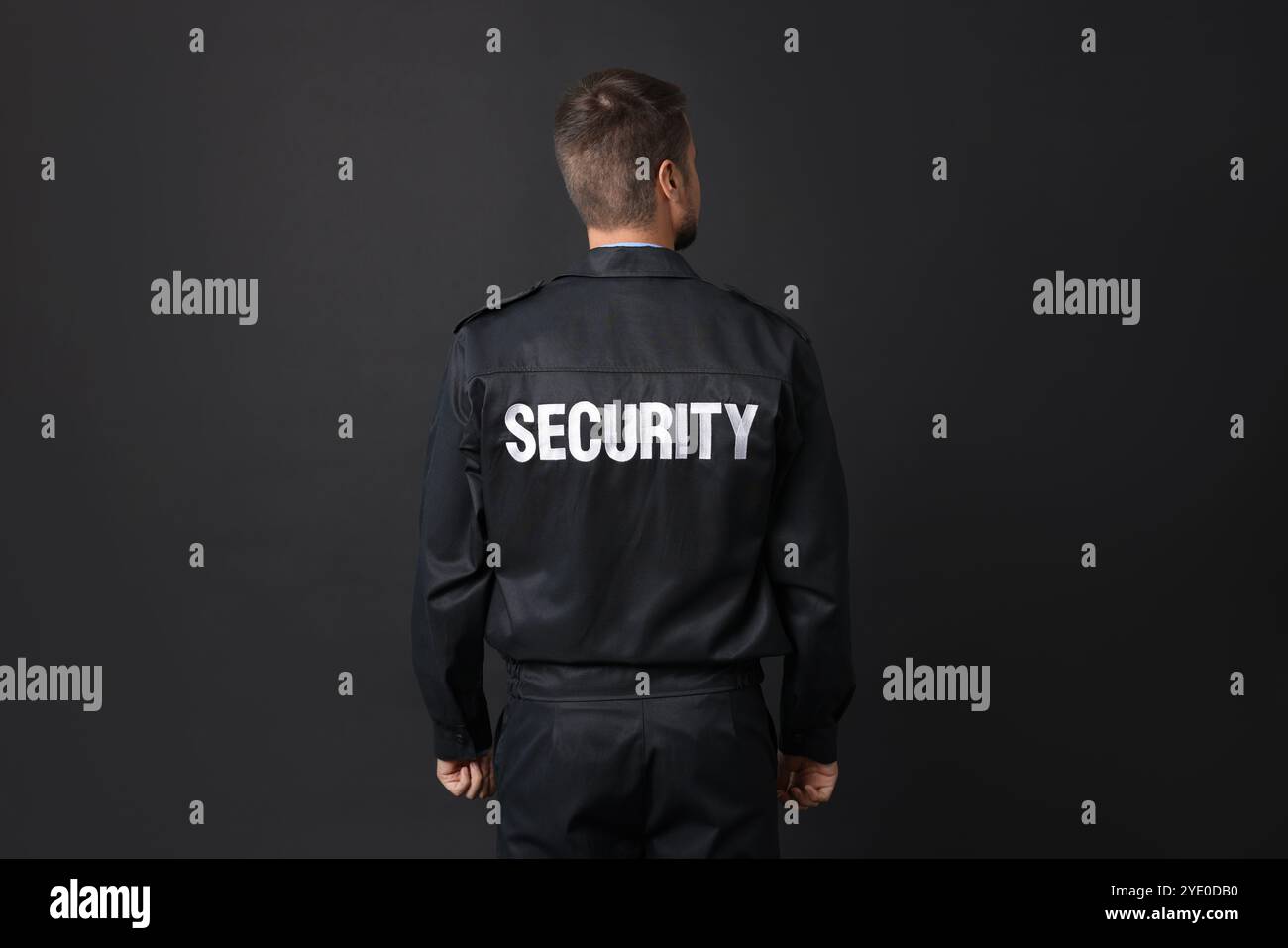 Security guard in uniform on black background, back view Stock Photo ...