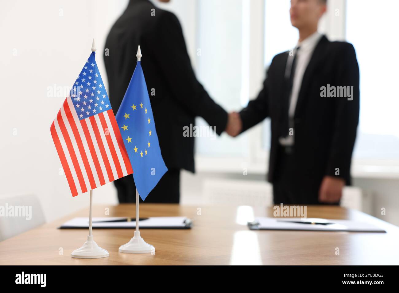 Diplomats shaking hands during meeting indoors, focus on flags of USA ...