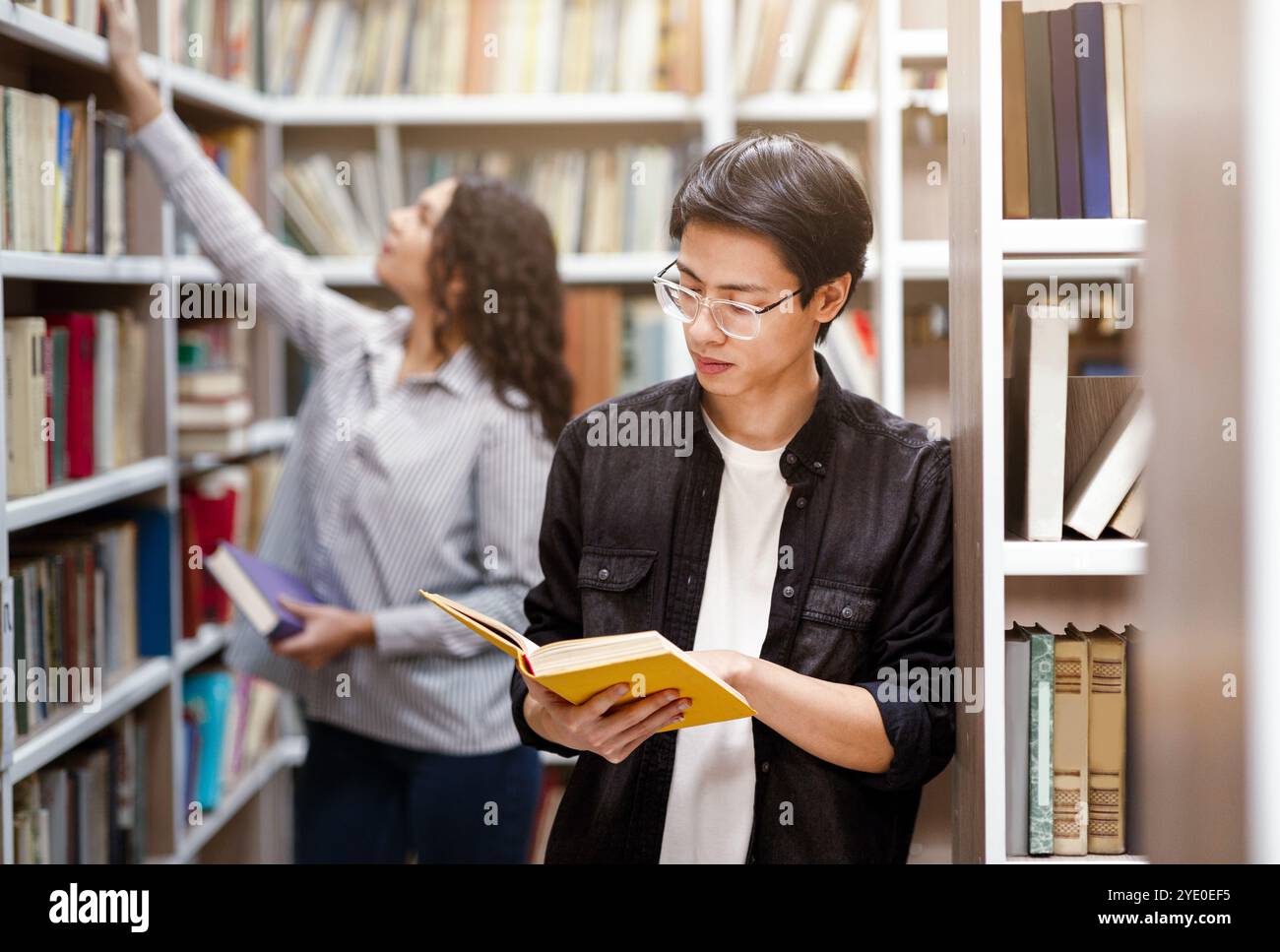 Focused japanese guy reading book at library Stock Photo - Alamy