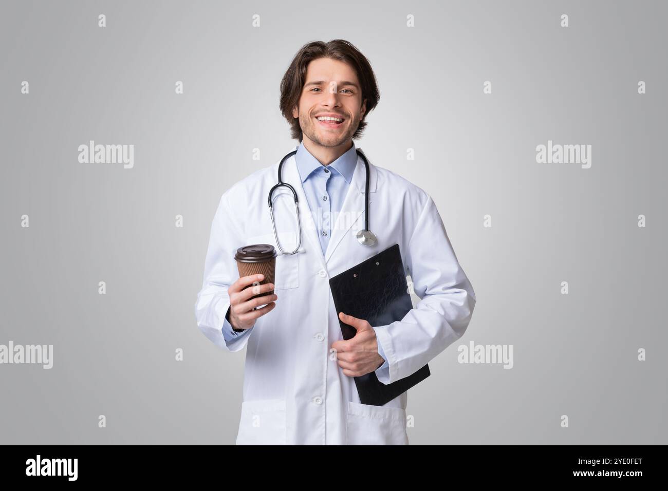 Portrait of young smiling doctor holding medical chart and takeout ...