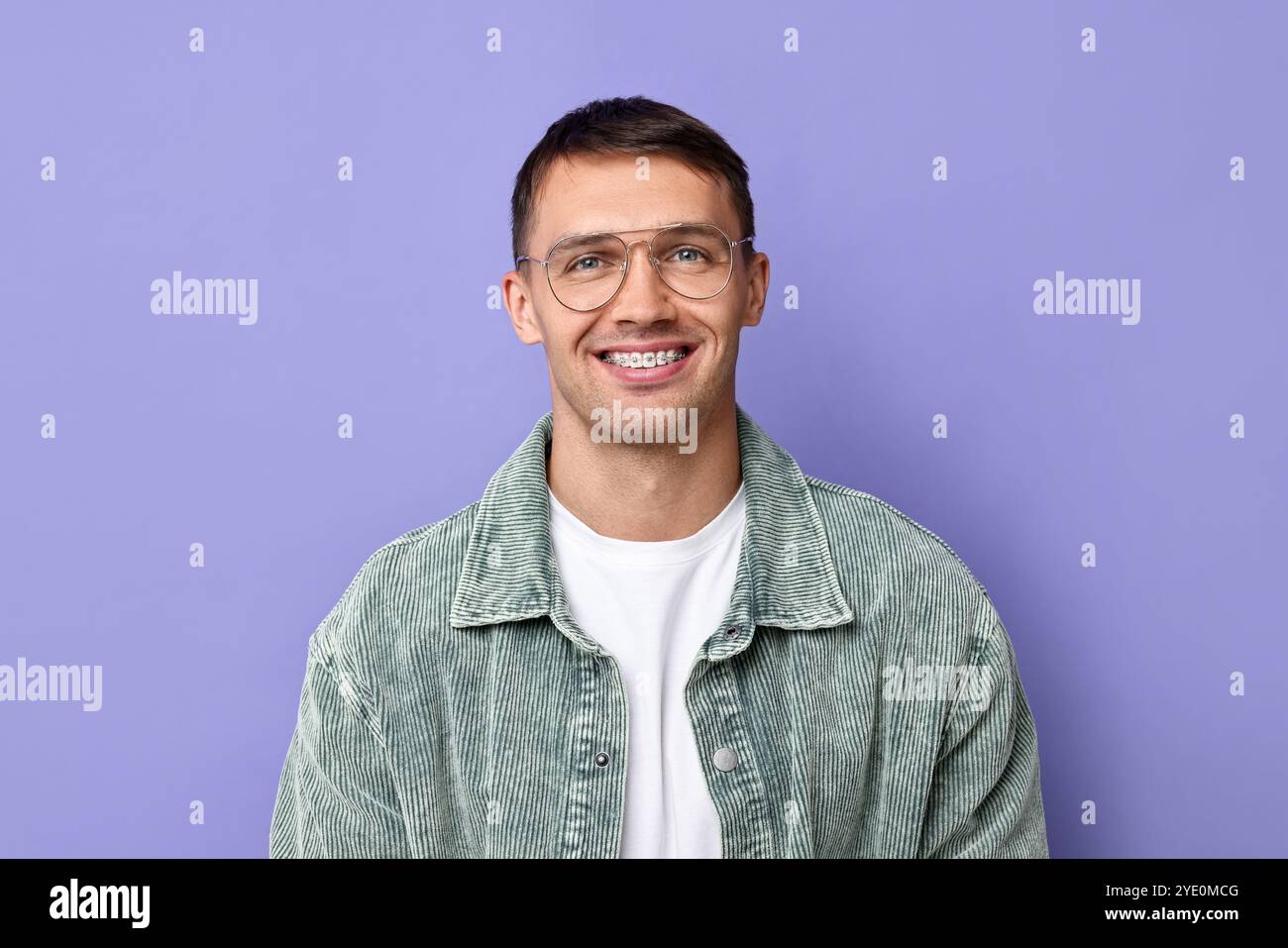 Smiling man with dental braces on violet background Stock Photo - Alamy