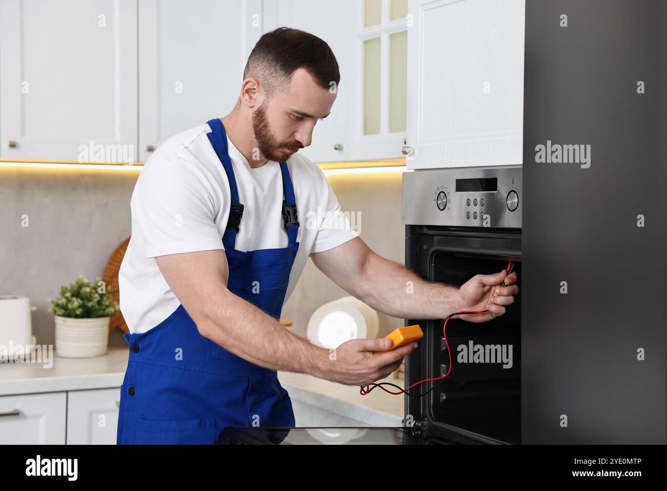 Repairman testing oven element with multimeter in kitchen Stock Photo ...
