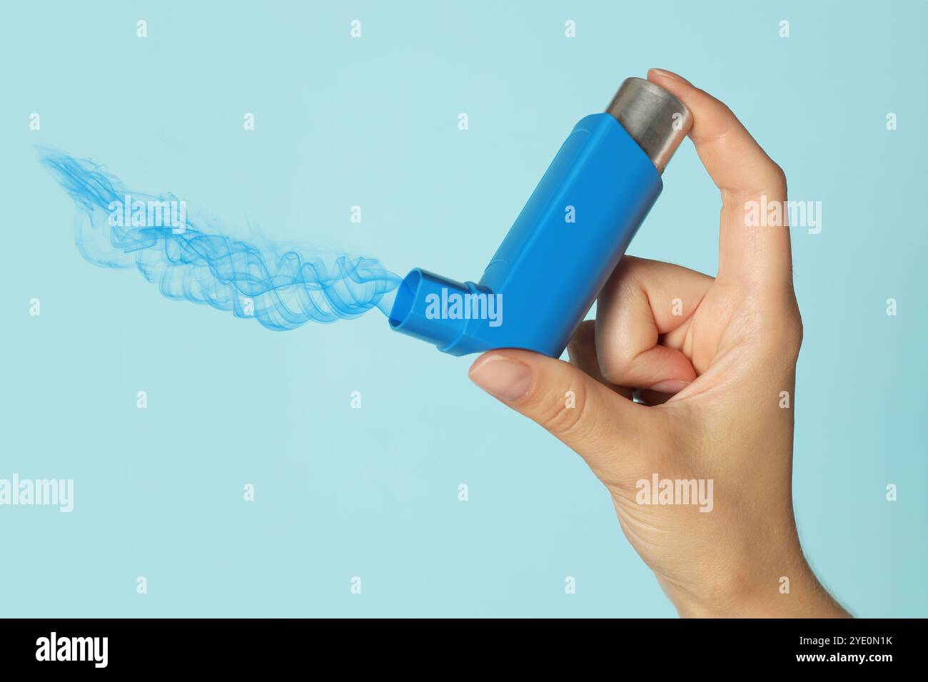 Asthma treatment. Woman holding inhaler on light blue background ...