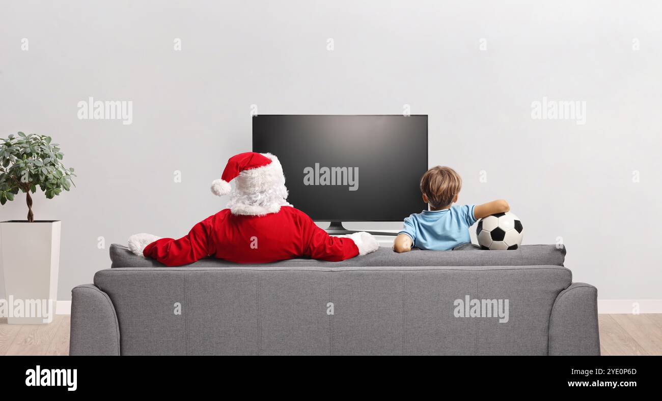 Santa claus and a boy watching tv at home seated on a sofa Stock Photo ...