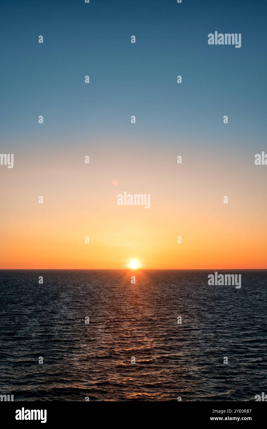 Baltic sea at sunset. Clear sky with glowing golden sun, reflections in ...
