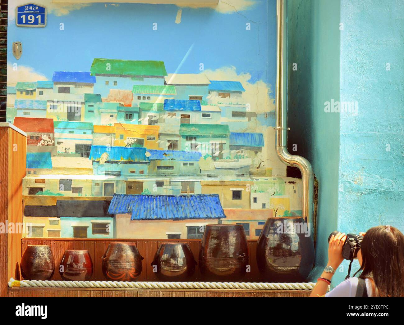 Woman taking a picture of a mural artwork in Gamcheon Culture Village ...