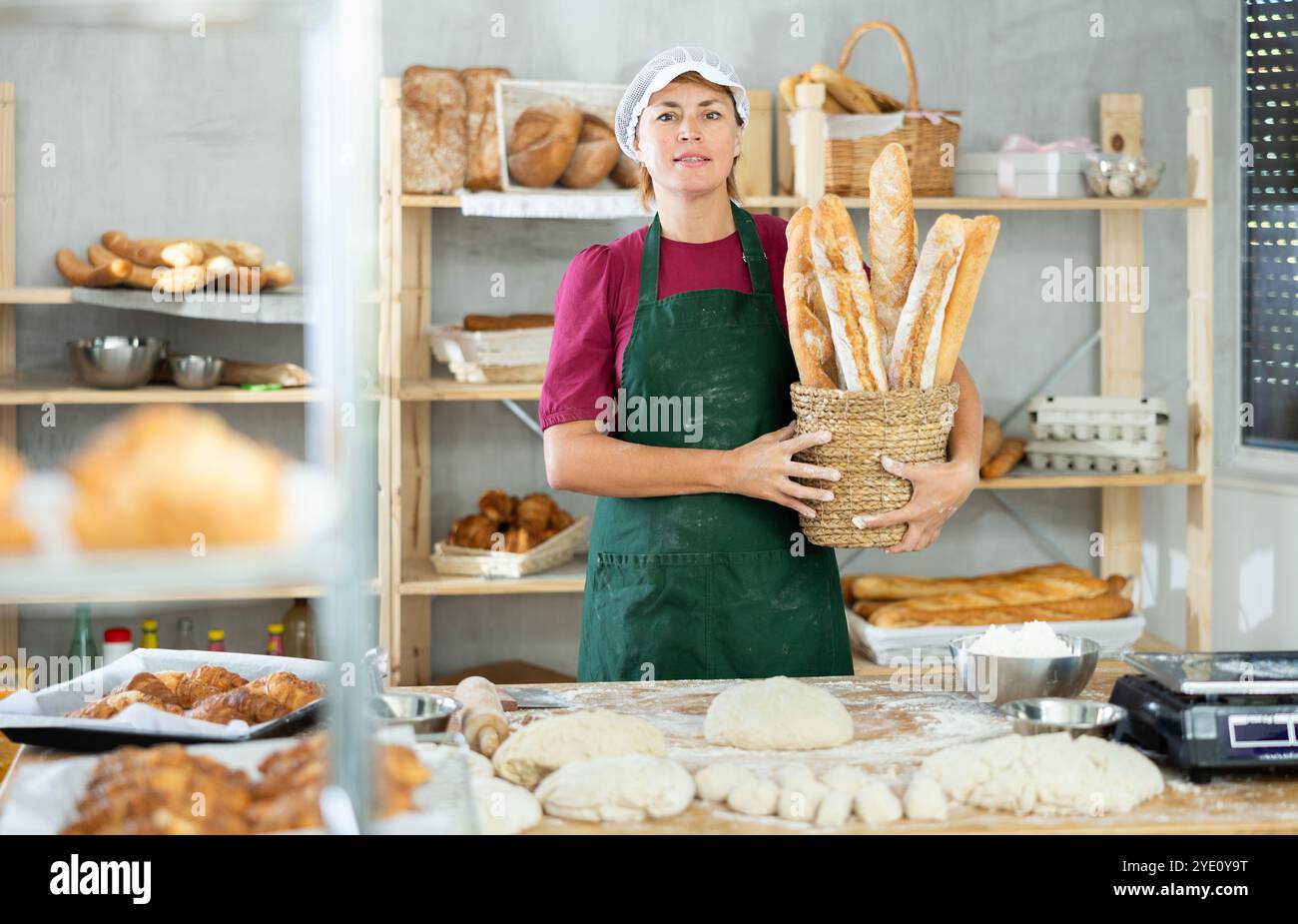 Adult female baker with basket of baguettes Stock Photo - Alamy