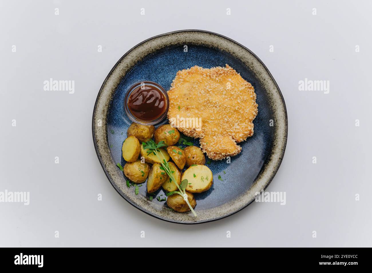 Crispy breaded chicken schnitzel with roasted potatoes and sauce ...