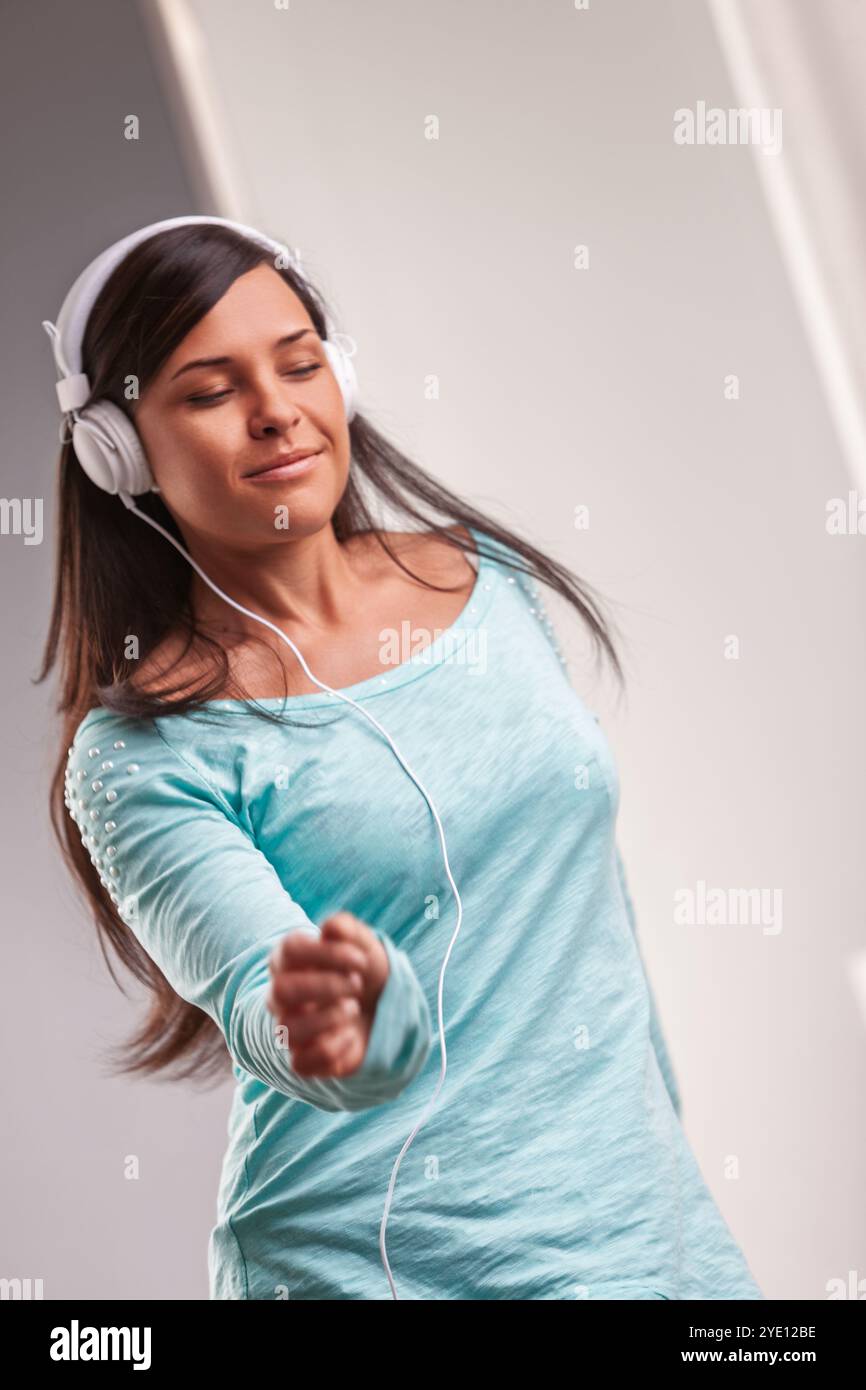Joyful young woman dances to music with headphones, eyes closed in ...