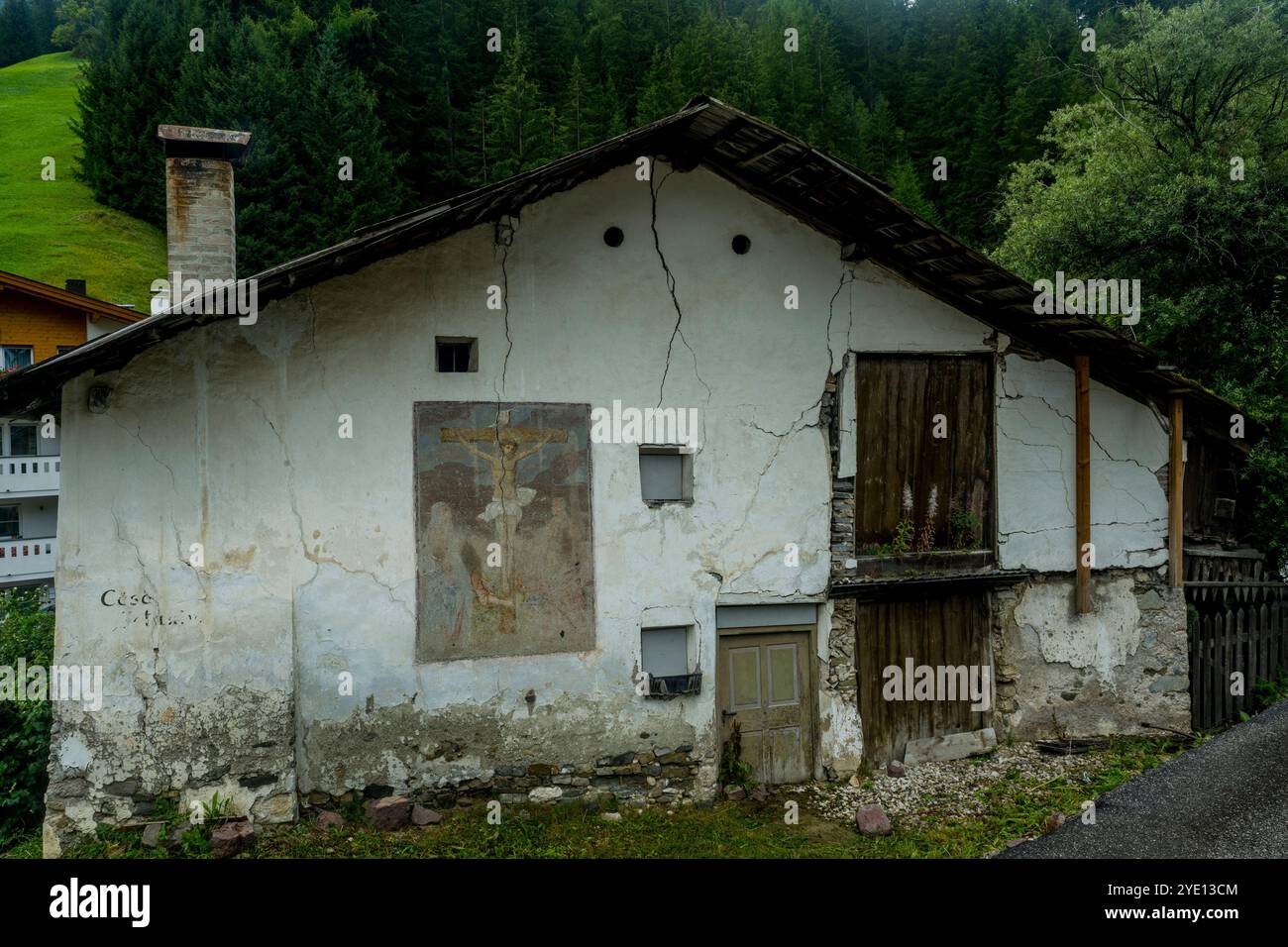 Street scene with an old abandoned house with a painting of the crucifixion of Jesus, town of ...