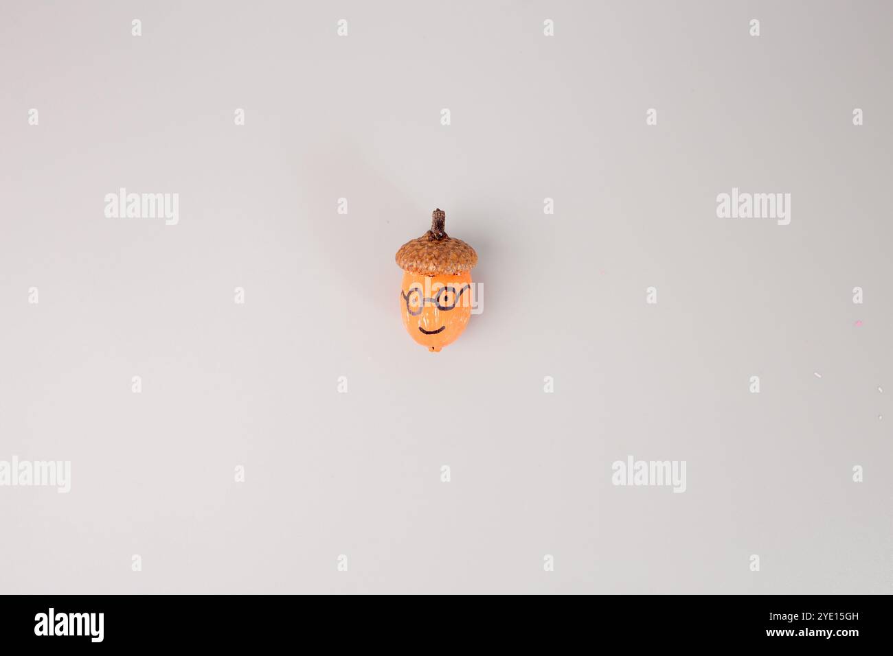 an acorn with a brown cap and a light brown body against a solid light ...