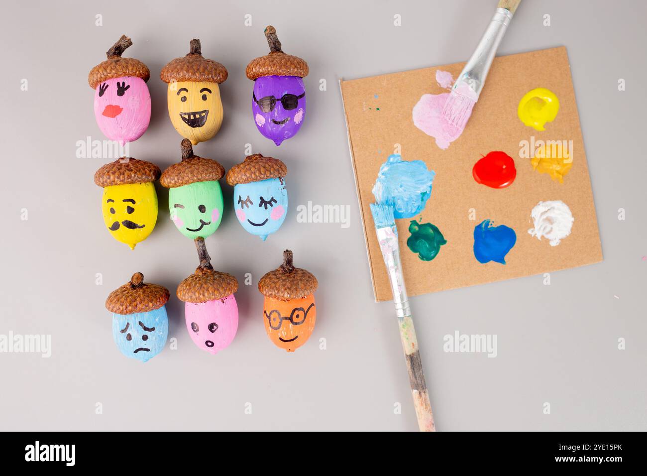 a collection of painted acorns arranged on a grey background. Each ...