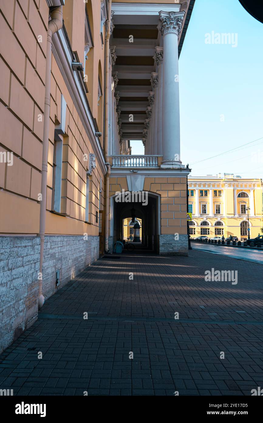 Sidewalk alongside a historic building with a colonnade and archway ...