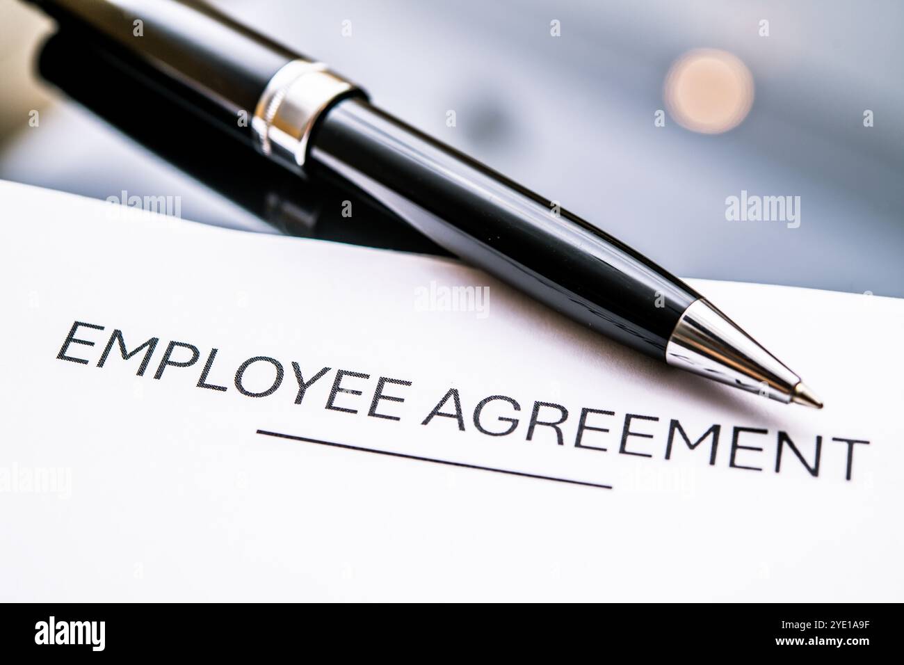 A detailed view of an employee agreement document alongside a pen ...