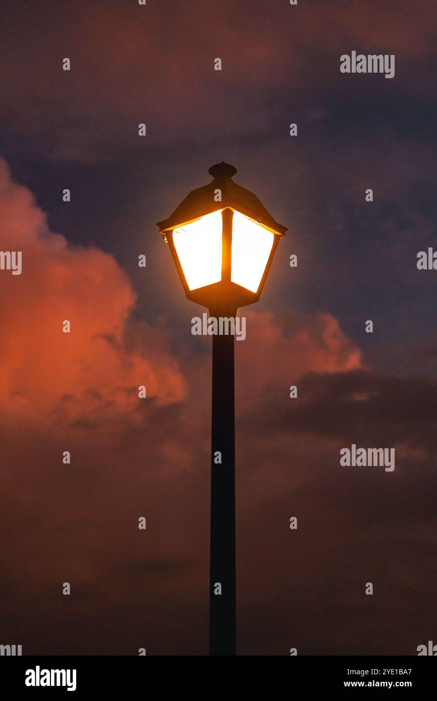 A Glowing Street Lamp Illuminates The Dramatic Evening Sky, Casting ...