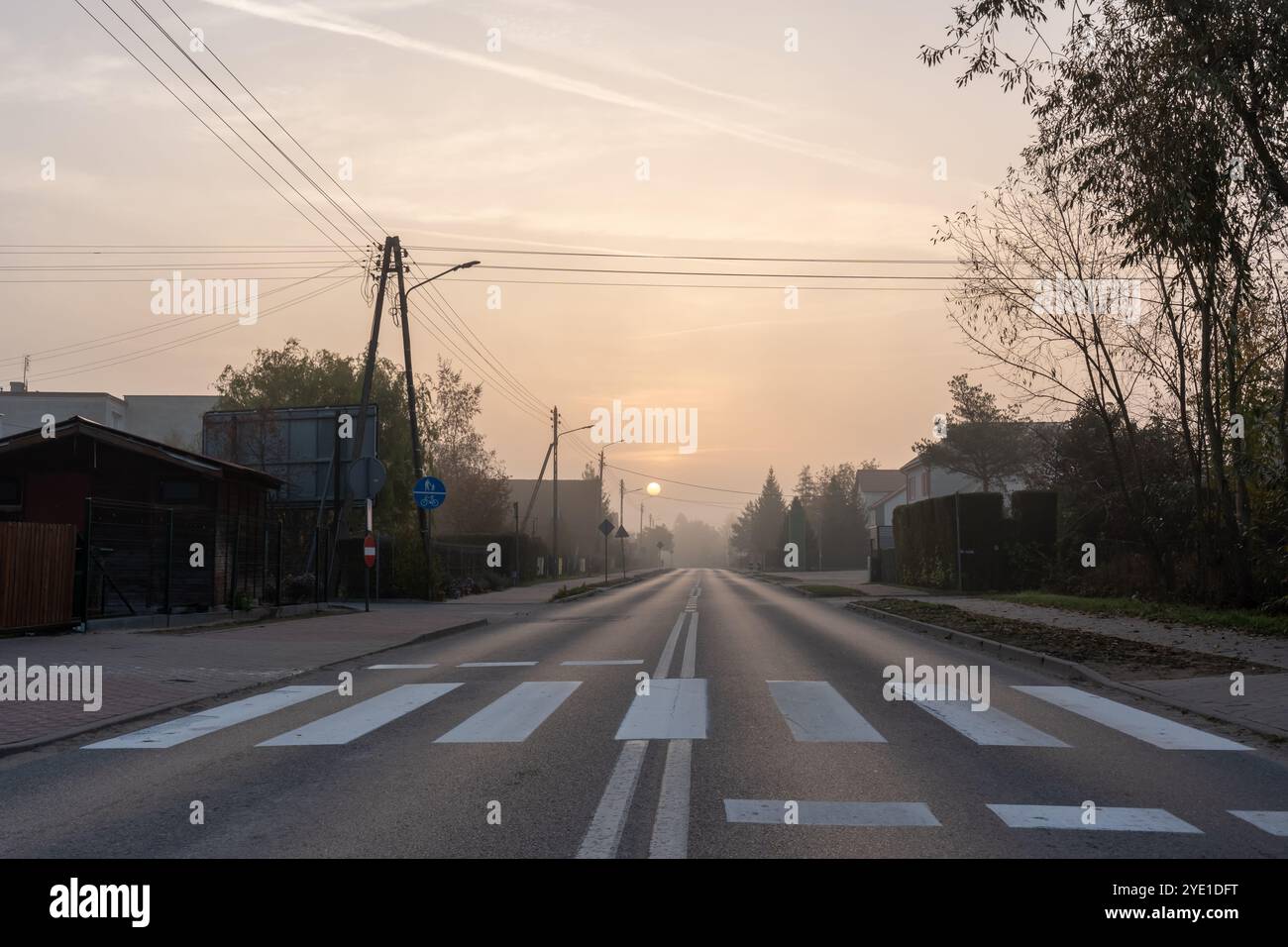 Empty suburban street at dawn with pedestrian crosswalk under soft ...