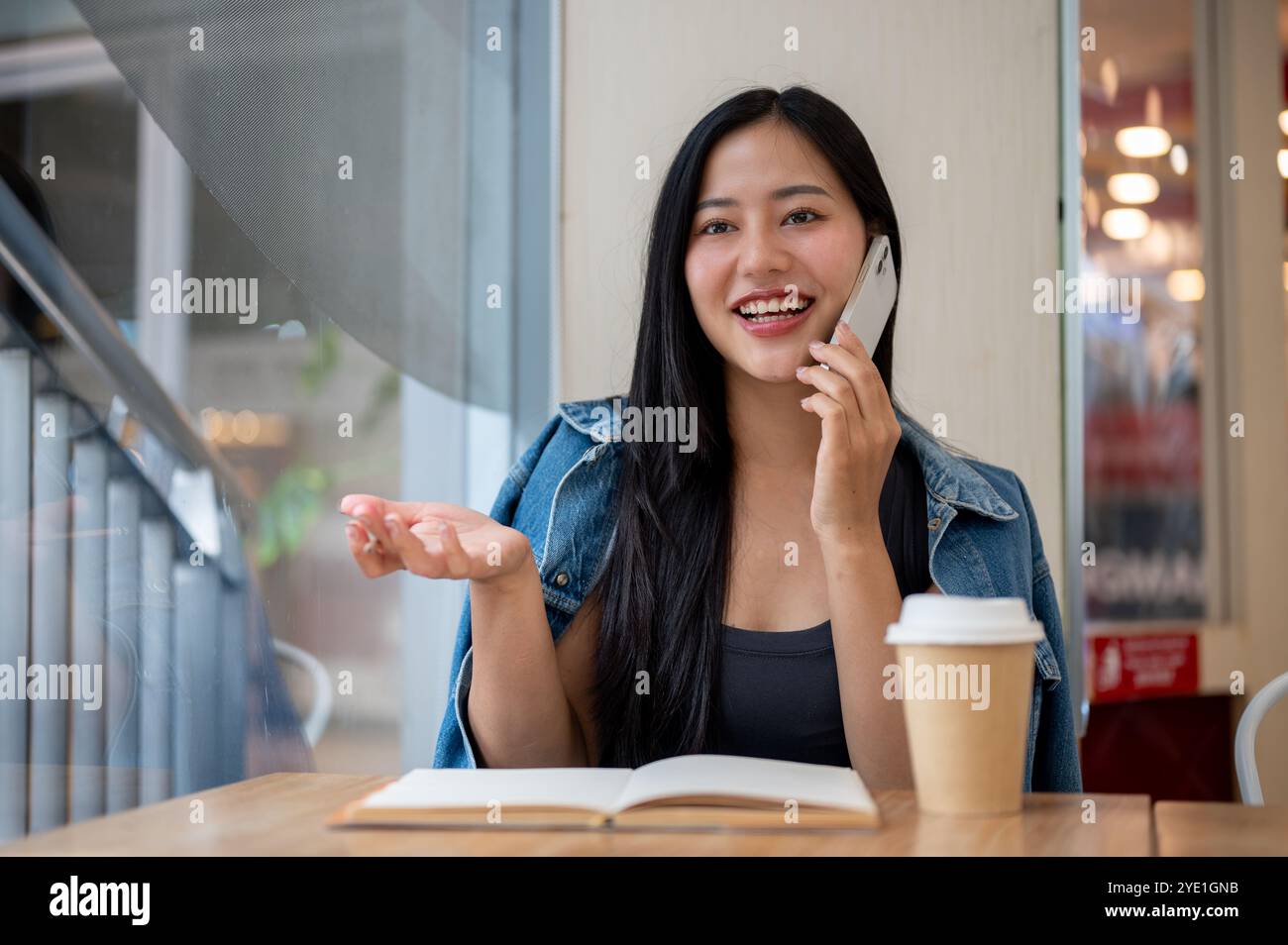 An attractive, smiling Asian woman is having a conversation with her ...