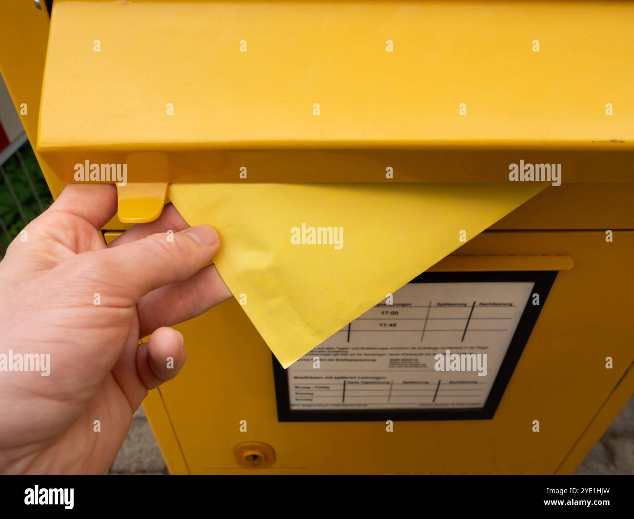 Posting a yellow letter into a mailbox im Germany. Sending an empty ...