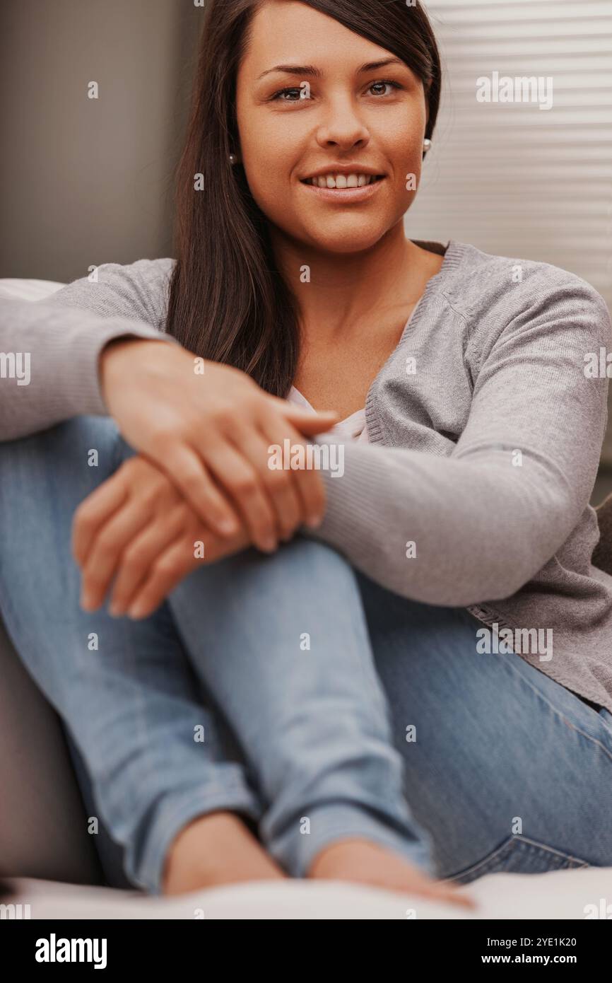 Secure and self assured young woman sitting comfortably, embracing her ...