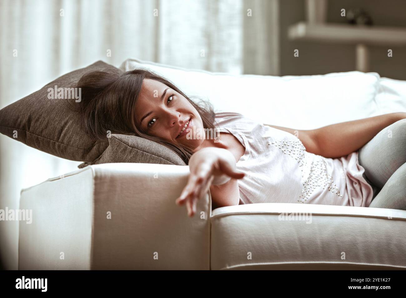 Young woman is lying down and relaxing on a comfortable sofa in a ...