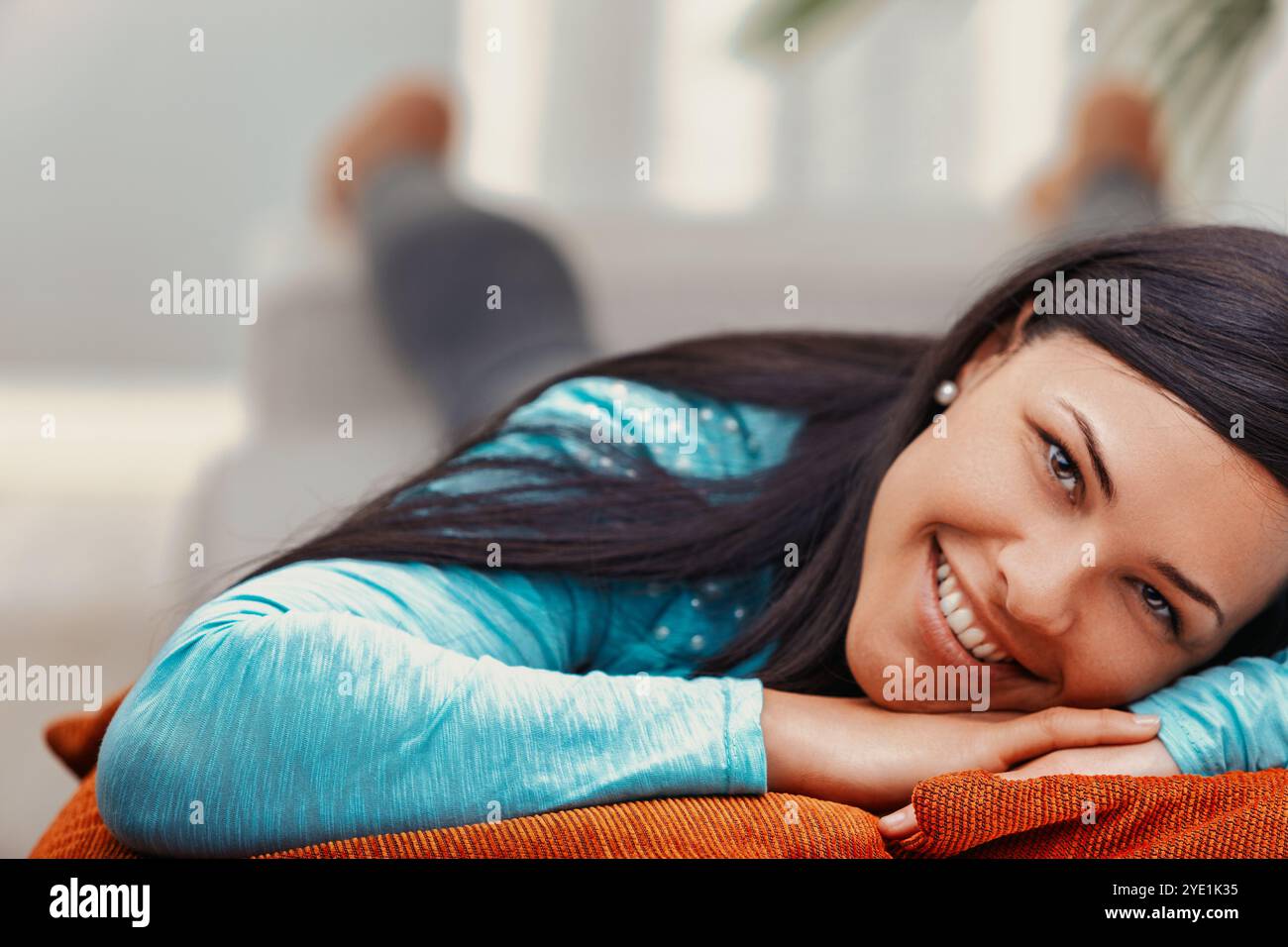 Young woman is lying on a comfortable sofa, resting her head on her ...