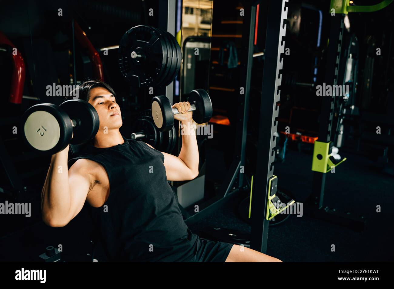 Asian man muscular lifting dumbbell on bench in fitness gym, Happy ...