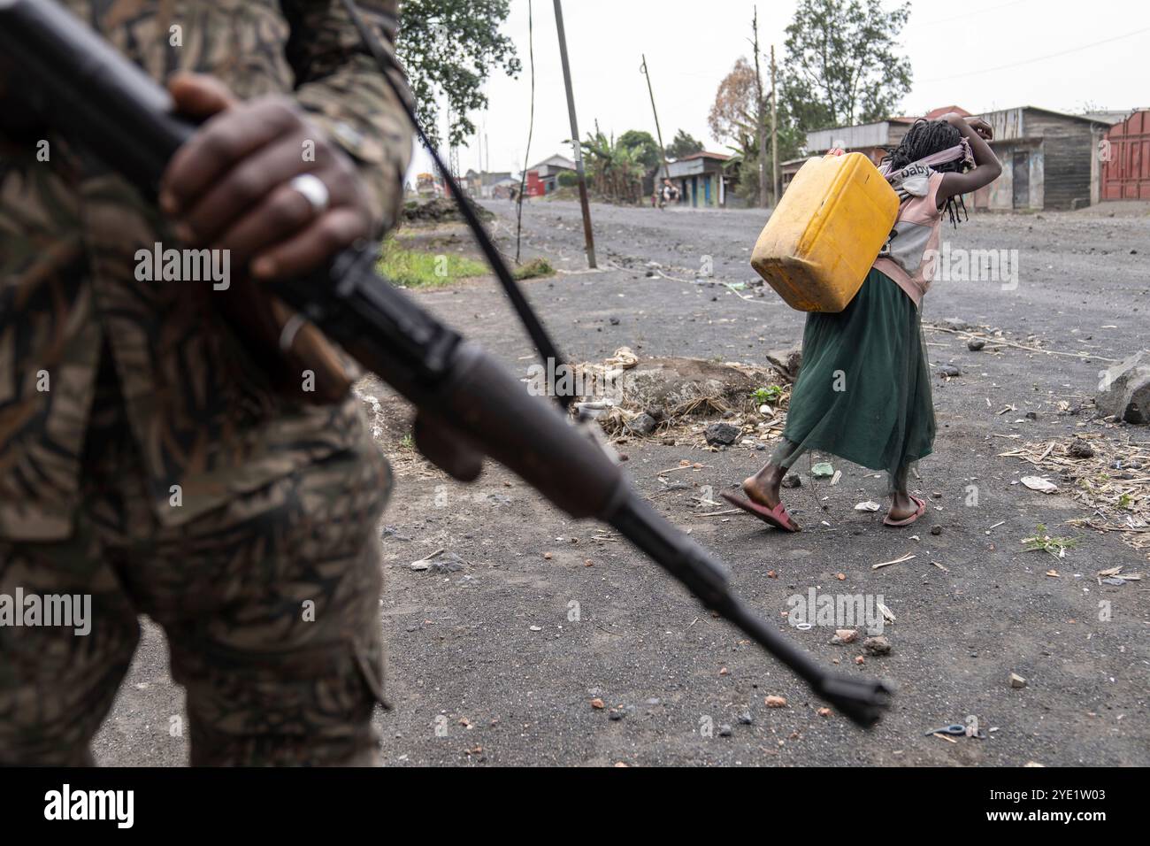 A child carrying water walks past Wazalendo forces fighting M23 rebels patrolling in Sake ...