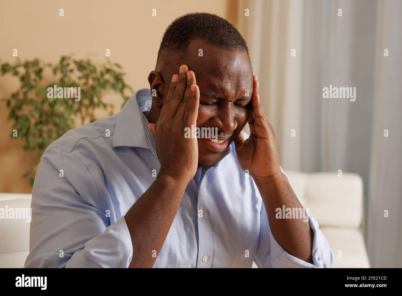 Close-up of an exhausted african american man experiencing headache ...