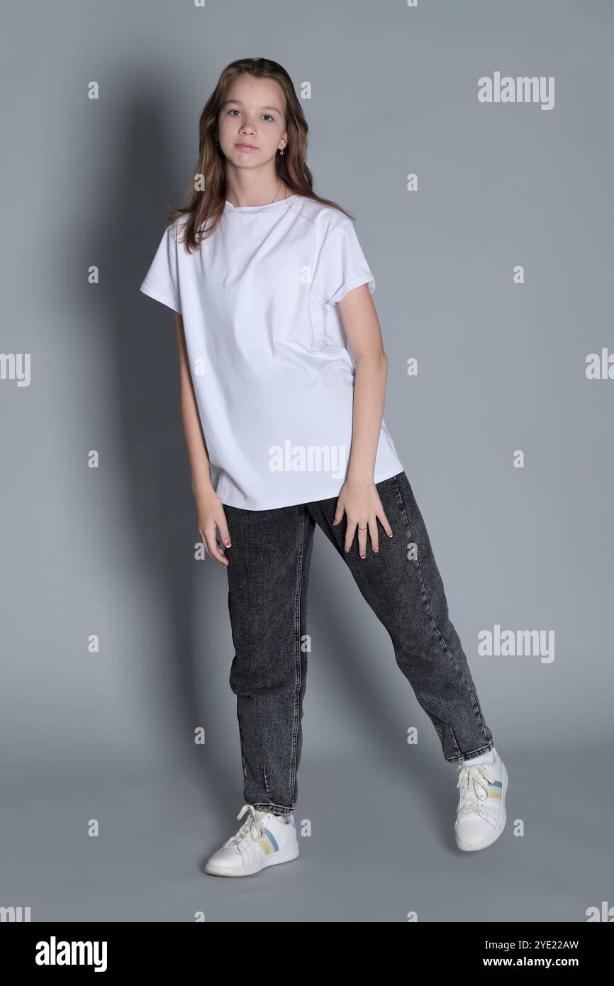 teenage girl stands casually with a slight lean, dressed in a simple ...