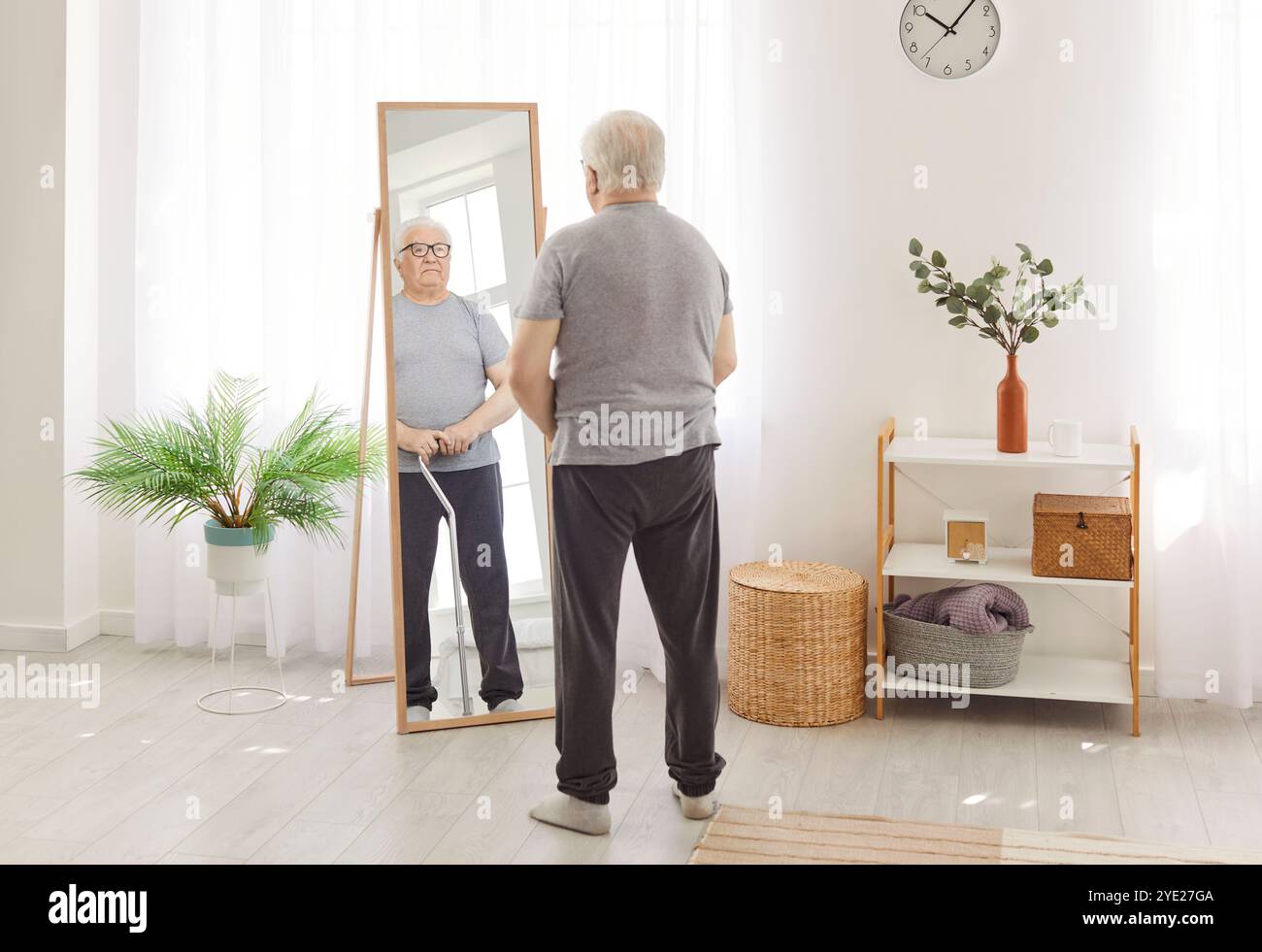 Senior man with a stick looking at his reflection in a full length ...