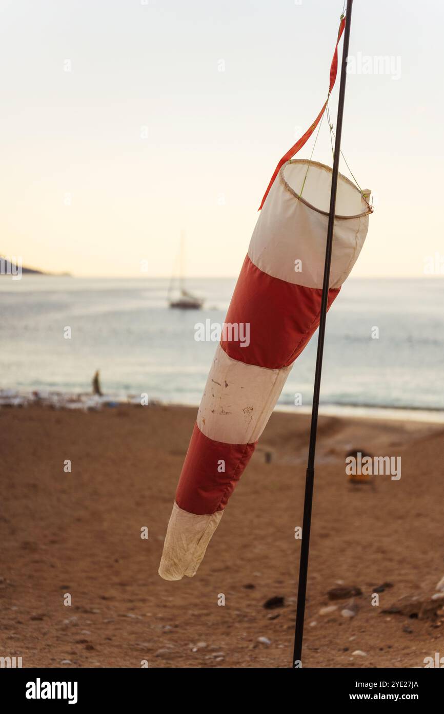A colorful red and white wind vane is hanging from a tall pole on the ...