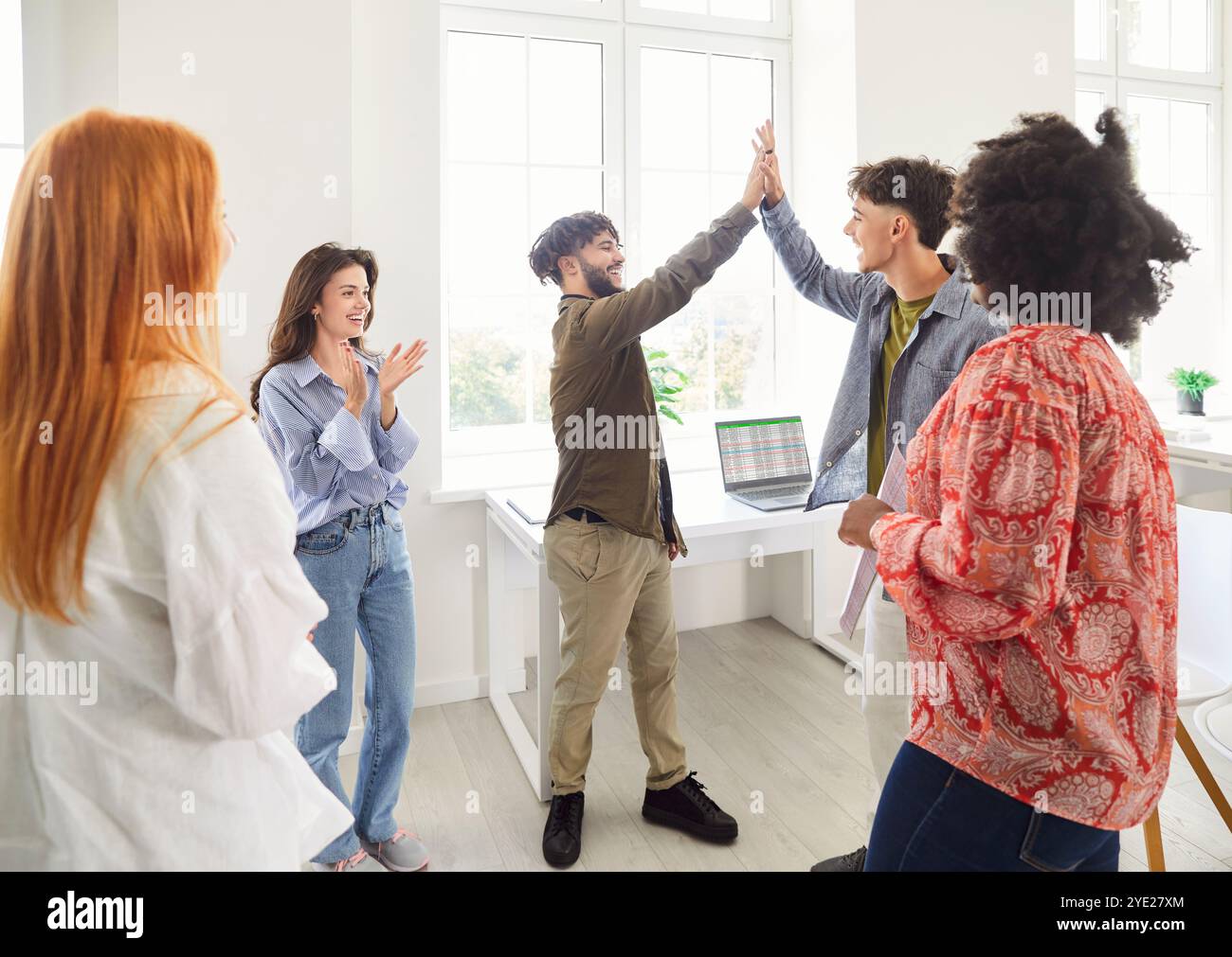 Diverse group of happy young colleagues celebrating success with two ...