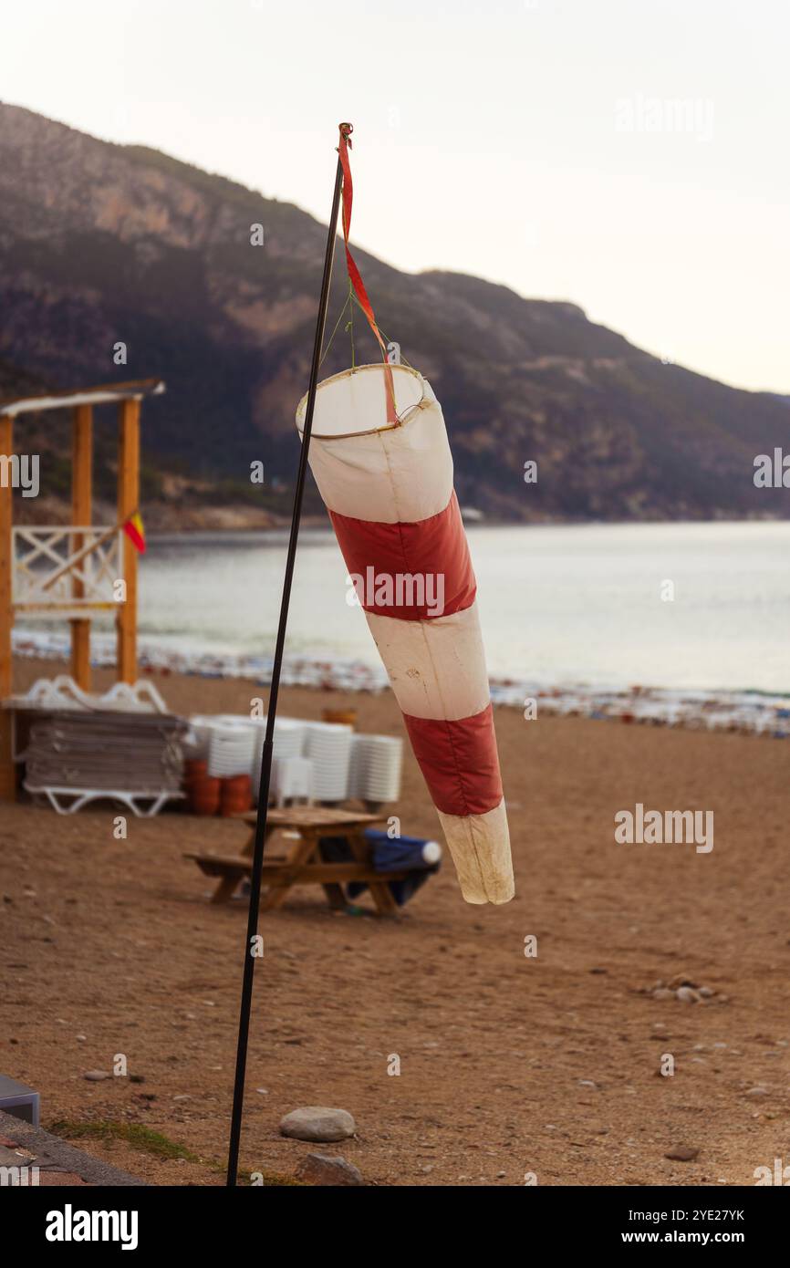 A colorful red and white wind vane is hanging from a tall pole on the ...