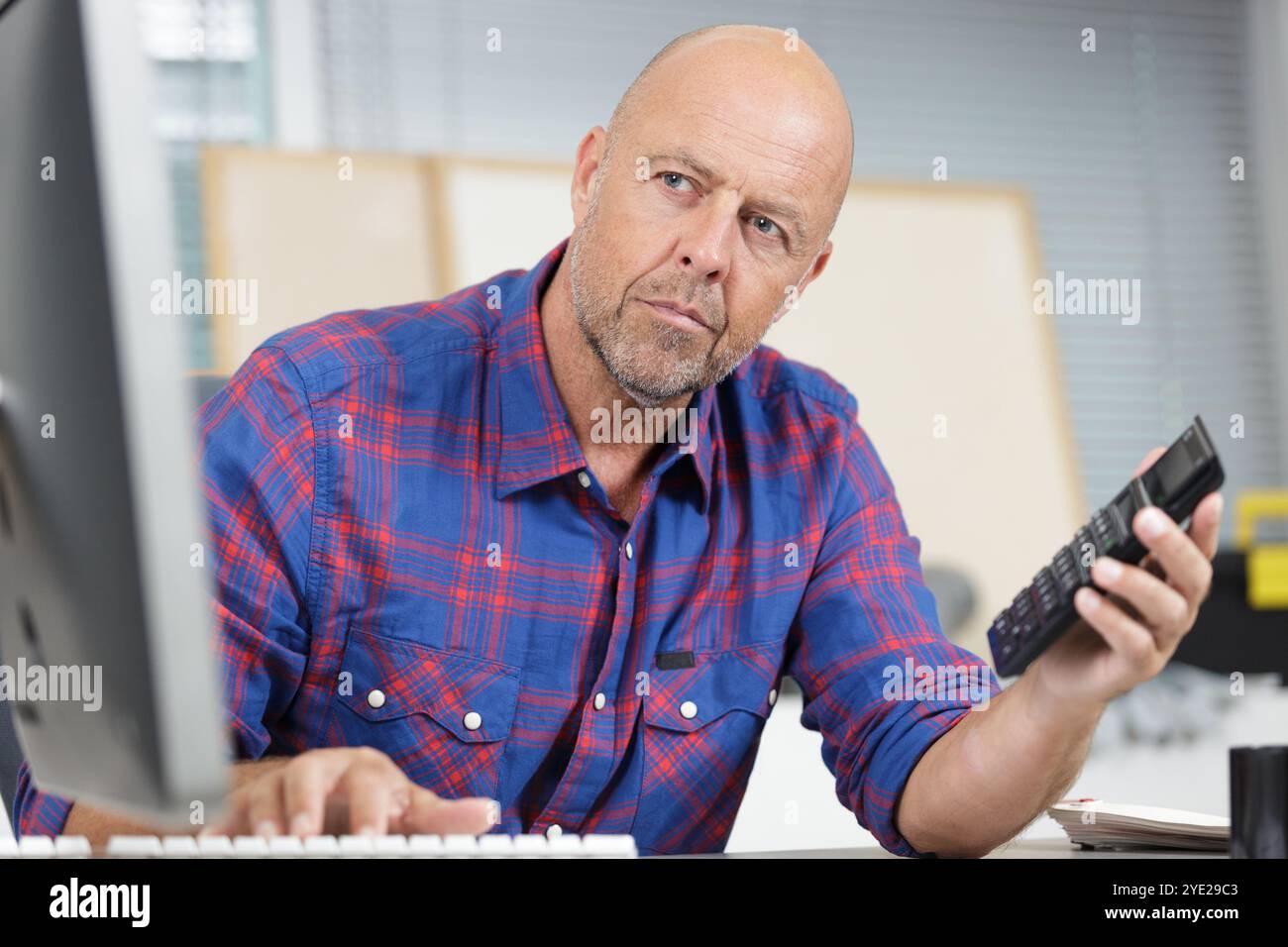mature worker with calculator in office Stock Photo - Alamy