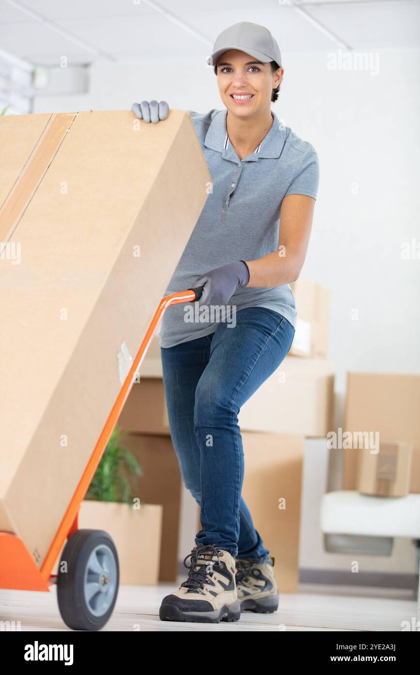 woman pushing voluminous carton on wheeled trolley Stock Photo - Alamy