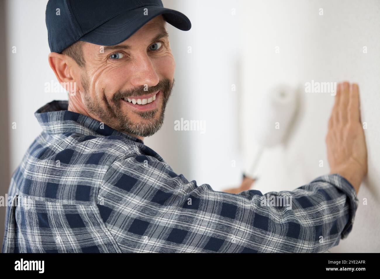 smiling painter with roller painting a wall Stock Photo - Alamy